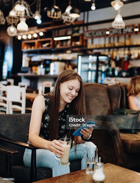 카페에서 미국 커피를 마시면서 스마트폰과 모바일 앱을 사용하는 젊은 여성 소매 소비자주의에 대한 스톡 사진 및 기타 이미지 소매 소비자주의 아름다운 여성 18 19세
