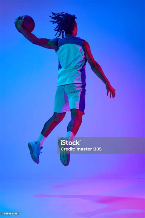 젊은 프로 운동선수 네온 불빛의 그라데이션 파란색 배경에 대해 경기 중 움직이는 농구 선수의 전체 길이의 역동적인 이미지 18 19세에 대한 스톡 사진 및 기타 이미지