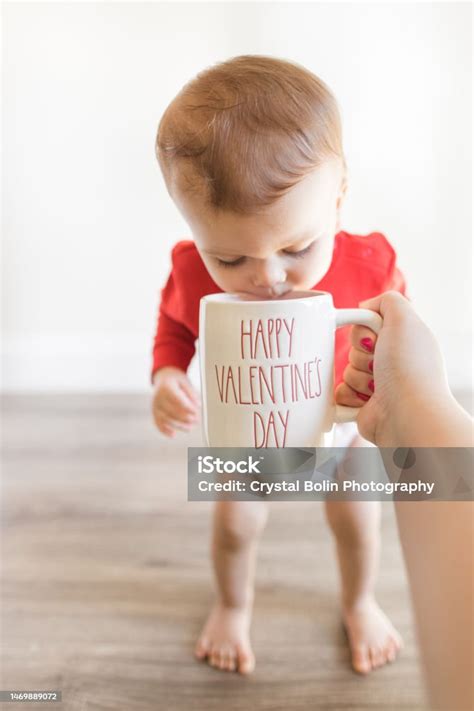 맨발로 귀여운 14개월 된 아기 Littlest Valentine이라고 적힌 빨간 스웨터를 입고 나무 나무 바닥에 앉아 있는 동안 천 기저귀를 차고 그의 엄마는 Happy