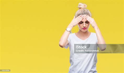 젊은 아름 다운 금발 여자는 스트레스 때문에 머리에 통증에 대 한 머리에 손으로 고립 된 배경 위에 흰색 티셔츠를 입고 고통 편두통 T 셔츠에 대한 스톡 사진 및 기타