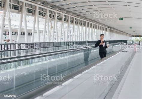 검은 양복을 입은 젊은 아시아 사업가가 전화를 사용하고 커피 한 잔을 들고 복사 공간이 있는 고가 산책로 역에 서 있습니다 30 34세에 대한 스톡 사진 및 기타 이미지