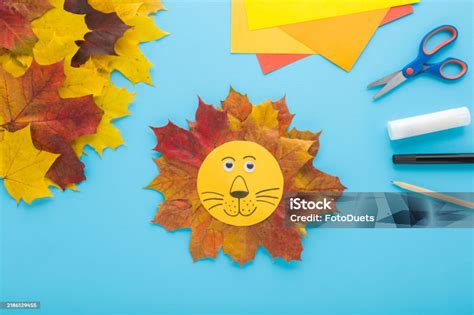 밝은 파란색 테이블 배경에 화려한 단풍 잎과 종이로 만든 아름 다운 웃는 사자 머리 모양 파스텔 색상 가을 장식 만들기 근접 촬영 하향식 보기 0명에 대한 스톡 사진 및