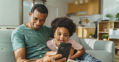 집에서 스마트폰을 사용하는 흑인 아프리카계 미국인 아버지와 아들 행복한 미소를 짓고 있는 아프리카 남자와 화상 통화를 하는 어린 아이 사진 Unsplash의 전화 사용 이미지