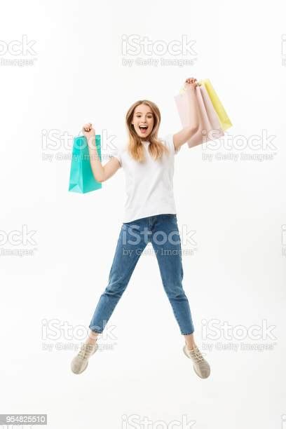 점프 하 고 흰색 배경에 고립 된 카메라를 보고 있는 동안 쇼핑백을 들고 행복 한 예쁜 여자의 전체 길이 초상화 명랑한에 대한 스톡 사진 및 기타 이미지 Istock