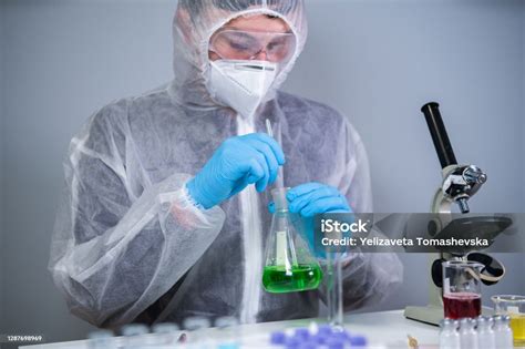 비커에 녹색 액체를 흔들고 과학자 실험실에서 테스트 또는 연구를 만드는 젊은 실험실 도우미 기술자 테스트 화학 실험실 실험 및 현미경과 함께 유리 튜브 플라스크를 흔들어