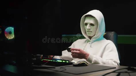 A Masked Hacker Breaks Into A Database On A Computer Hacking In A Dark