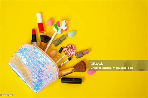 여성용 화장품 세트 파우더와 블러셔 용 브러쉬 파운데이션용 스폰지 립스틱 매니큐어 노란 배경에 화장품 가방에서 흩어져 있는 향수 병 상단 보기 복사 공간 가루로 빻은에 대한