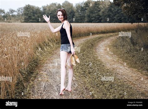 Young Girl Walking Barefoot On The Ground Road Through Field And Forest