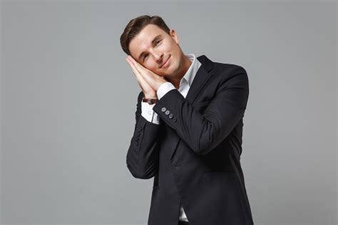 회색 벽 배경에 고립 포즈 고전적인 검은 정장 셔츠에 젊은 사업가 를 미소 성취 경력 재산 사업 개념 복사 공간을 모의합니다 뺨