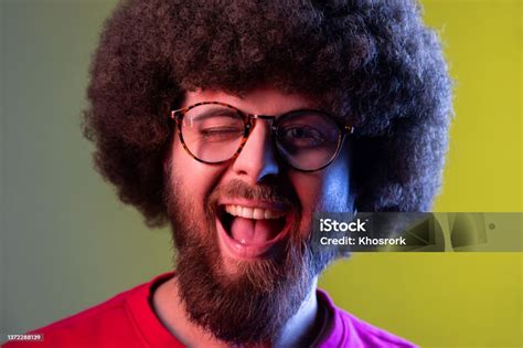 카메라를 바라보며 윙크를 하며 긍정적인 감정을 표현한 아프로 헤어스타일을 가진 남자 눈 깜박임에 대한 스톡 사진 및 기타 이미지