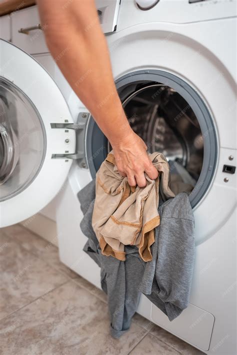 Premium Photo Womans Hand Introducing Dirty Clothes In A Washing