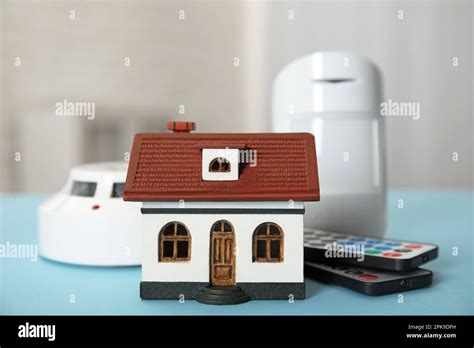 House Model Remote Controls Smoke And Movement Detectors On Light Blue Table In Room Home
