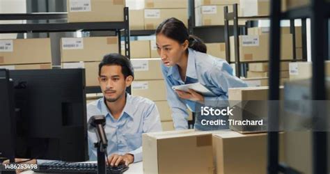 มีความสุขชายเอเชียและผู้หญิงหุ้นส่วนสวมเสื้ออย่างเป็นทางการนั่งอยู่หน้าโต๊ะคอมพิวเตอร ภาพสต็อก