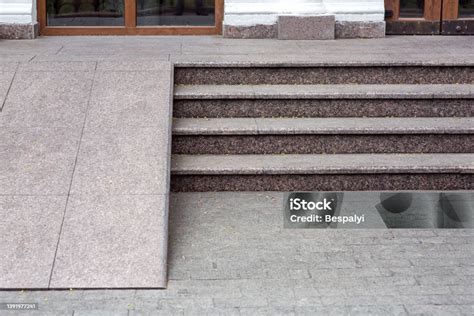 장애인을위한 휠체어 경사로를 사용하여 접근 할 수 있습니다 유리 문 클로즈업 정면보기가있는 카페 입구의 돌 타일 계단 근처의 화강암 램프 통로 아무도 0명에 대한 스톡 사진