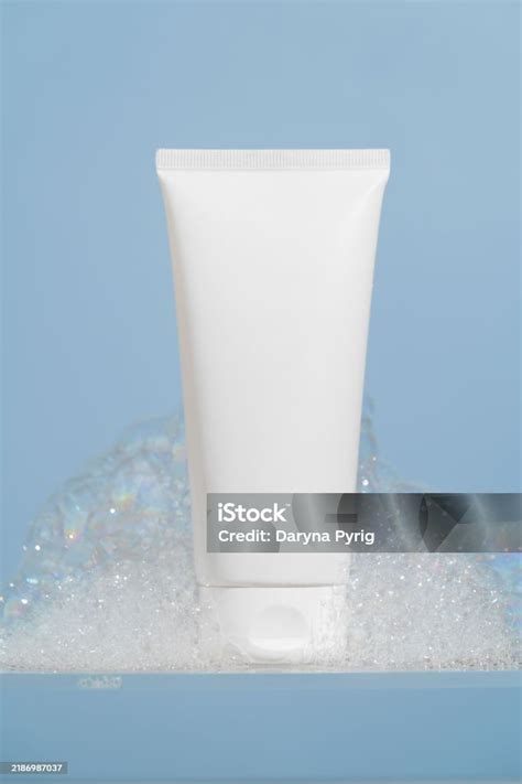 거품이 있는 파란색 고립된 배경에 크림 또는 로션의 흰색 모형 튜브의 수직 이미지 얼굴과 바디 케어의 개념 피부를 정화하고 보습하는 미용 제품 0명에 대한 스톡 사진 및