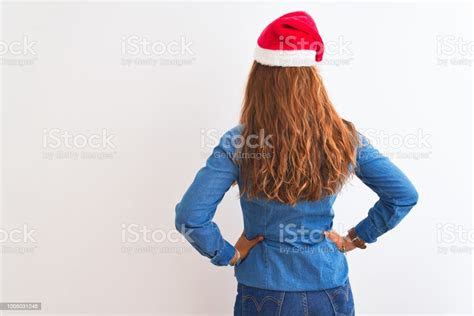 고립된 배경 위에 크리스마스 모자를 쓰고 있는 젊은 아름다운 빨간 머리 여자는 몸에 팔을 들고 뒤로 서 있습니다 사람들에 대한 스톡 사진 및 기타 이미지 Istock
