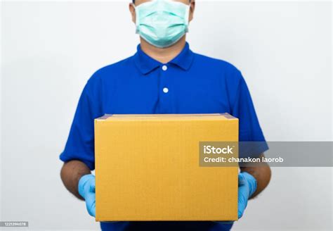 배달 남자 블루 유니폼 고무 장갑을 착용 하 고 흰색 배경에 소포 판지 상자를 들고 마스크 배달부에 대한 스톡 사진 및 기타 이미지 Istock