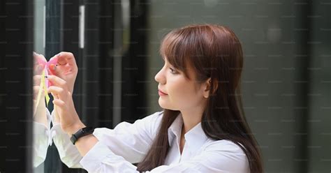 현대 사무실에서 유리 벽에 스티커 메모를 붙이는 여성 회사원 사진 Unsplash의 태국 이미지