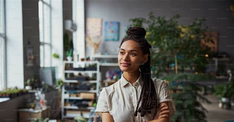 작업장에 서 있는 콘로우를 가진 차분한 매력적인 여성 꽃집의 허리 위로 초상화 사진 Unsplash의 인테리어 디자이너 이미지