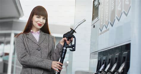 매력적인 미소를 짓고 있는 젊은 백인 여성의 초상화를 클로즈업하고 급유 가솔린 노즐을 들고 주유소에서 카메라를 향해 포즈를 취합니다 사진 Unsplash의 우크라이나 이미지