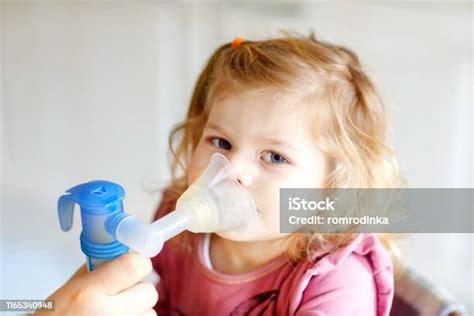 집에서 분무기로 흡입하는 어린 유아 소녀 아버지 또는 어머니가 장치를 돕고 들고 있습니다 독감 기침 및 기관지염을 가진 아이 천식 흡입기 흡입 증기 아픈 개념 건강관리와