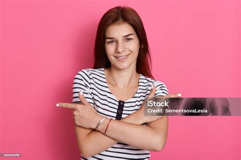 쾌활한 어두운 머리 의 여자는 가슴 포인트 왼쪽과 오른쪽 에 팔을 교차 두 가지 변종을 제공 제품을 광고 여성은 분홍색 배경에