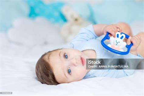 젖니가 나기 위한 설치류 또는 잠자는 침대에 딸랑이가 있는 아기 파란색 바디수트를 입은 건강하고 행복한 작은 아기 6 11 개월에 대한 스톡 사진 및 기타 이미지 Istock