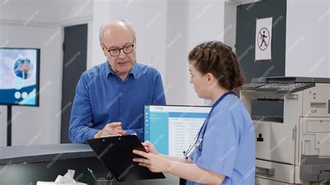 Premium Photo Medical Assistant And Old Patient Filling In Checkup Report Papers At Hospital