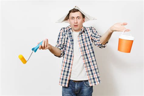 벽 그림에 대 한 페인트 롤러 손과 빈 페인트 통 복사 공간 흰색 배경에 고립으로 확산 신문 모자에 충격된 남자 리노베이션 객실에 대 한 도구입니다 수리 가정 개념입니다