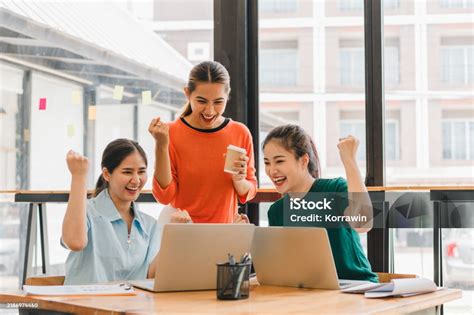 현대 사무실에서 노트북으로 작업하는 동안 성공을 축하하는 흥분한 여성들 그들의 즐거운 표정은 협업 환경에서의 팀워크와 성취를 반영합니다 25 29세에 대한 스톡 사진 및