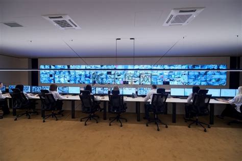 在闭路电视监控室工作的一组安全数据中心操作员查看多个监视器高清摄影大图 千库网