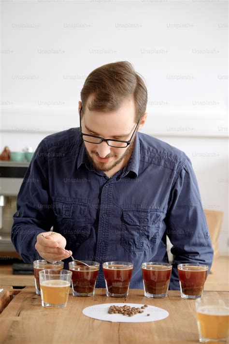 유리 컵에서 갓 내린 커피를 시음하는 남자의 초상화 숟가락을 사용하여 바로스타에 대한 커피 커핑 테스트에서 커피 맛과 풍미를 검사 사진 Unsplash의 마시다 이미지