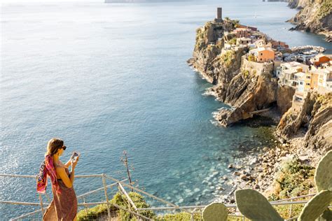 여자는 오래된 베르나차 마을과 함께 아름다운 해안선 풍경을 즐기며 이탈리아 북서부의 유명한 친퀘테레 마을을 여행합니다 지중해 연안 개념의 여름 휴가 넓은 시야 사진
