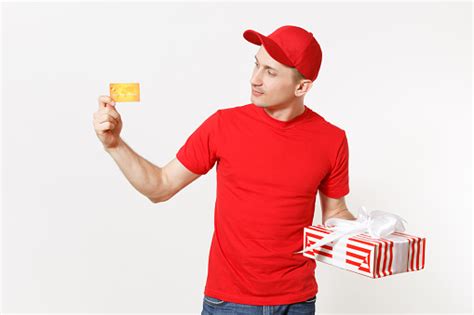 흰색 배경에 고립 된 빨간 유니폼에 배달 남자 모자 티셔츠 남성 청바지 택배 또는 신용 카드 빨간색 줄무늬 선물 상자와 딜러로 일 현재 광고에 대 한 공간을 복사 합니다