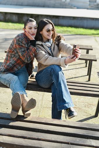 공원 벤치에서 휴식을 취하면서 함께 셀카를 찍는 웃는 여자 친구들 20 29세에 대한 스톡 사진 및 기타 이미지 20 29세