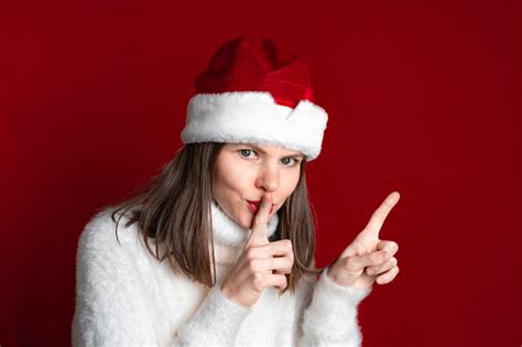 흰색 따뜻한 스웨터와 빨간 산타의 모자를 쓴 여성은 손가락으로 텍스트 나 디자인을위해 복사 공간에서 가리킵니다 가리키기에 대한 스톡 사진 및 기타 이미지 Istock