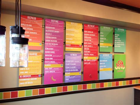 A Restaurant Menu Hanging On The Wall Next To A Counter With Several Different Colored Papers