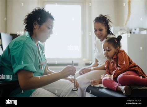 Female Pediatric Holding Reflex Hammer Discussing With Patient In