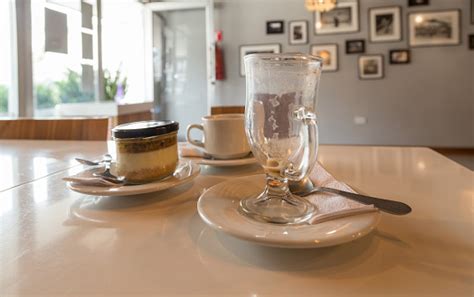 빈 유리 컵 접시와 숟가락이 있는 테이블은 다른 색상의 디저트 옆에 있으며 배경에는 사진과 함께 창문과 벽 현대적인 장식이 있습니다 0명에 대한 스톡 사진 및 기타 이미지