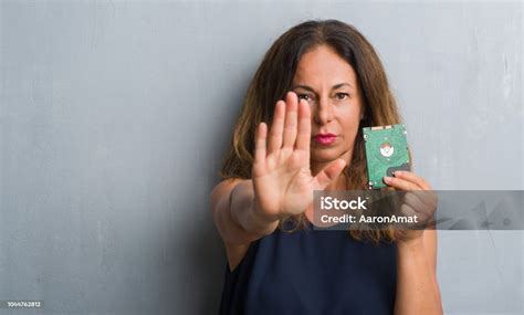 중세 스페인 여자 회색 그런 지 벽 오픈 손으로 심각 하 고 자신감 표현 방어 제스처 정지 표시를 하 고 하드 드라이브를 들고