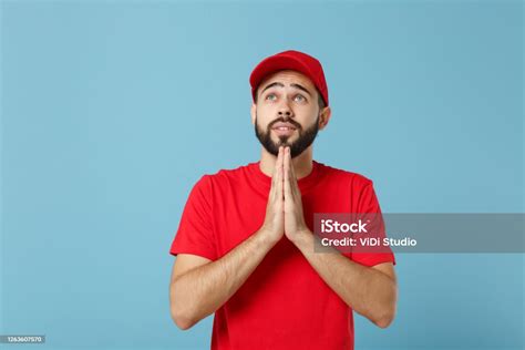 파란색 벽 배경 스튜디오 초상화에 고립 된 빨간색 유니폼 작업복을 입은 배달 남자 택배 딜러로 일하는 캡 티셔츠 프린트의 전문 남성 직원 서비스 개념 복사 공간을 모의합니다