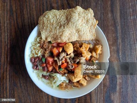 노란 국수 당면 쇠고기 고기 두부 템페 당근 토마토 볶은 양파 양배추 셀러리 튀긴 양파 땅콩 및 Krupuk Karak 크래커를 가진 Bakmi Toprak 또는