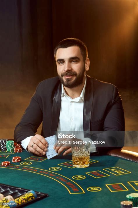 포커 테이블에 앉아 비즈니스 정장 한 젊은 남자가 있다 남자의 도박 카드 게임 테이블 게임에서 선수 카지노에 대한 스톡 사진 및
