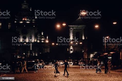 그들의 신혼 여행 야외는 밤에 잘생긴 남자와 손을 검은 양복에 잡고 검은 드레스 아름 다운 여자에 유럽 거리에서 산책에 행복 한 커플 모험 개념 커플에 대한 스톡 사진 및