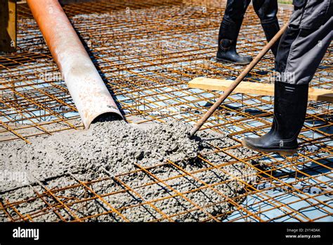 Worker Distributing Concrete Onto Rebar Framework For Slab Foundation