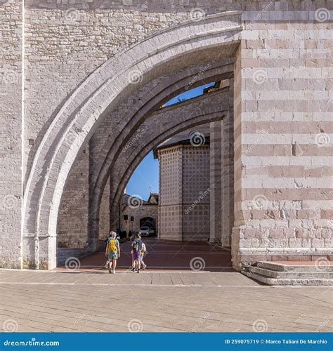 Tourists Walk Under The Flying Buttresses Of The Ancient Basilica Of Santa Chiara Assisi Italy