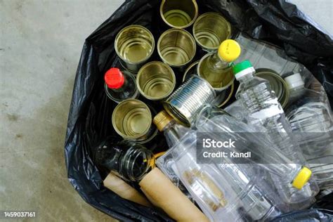 분류되지 않은 플라스틱 유리 병 금속 캔 용기 종이 판지를 시멘트 바닥에 검은 쓰레기 봉투에 모았습니다 폐기물 제로 지속 가능성 개념 선택적 초점 왼쪽에 공간을 복사합니다