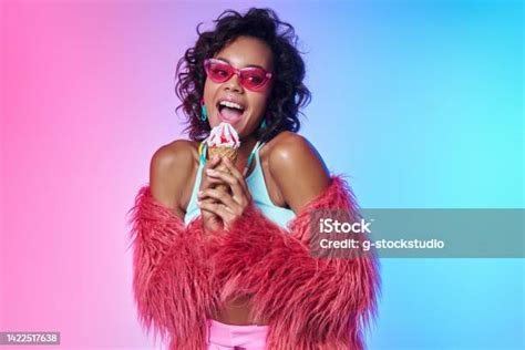 화려한 배경에 아이스크림을 즐기는 푹신한 재킷을 입은 아름다운 아프리카 여성 먹기에 대한 스톡 사진 및 기타 이미지 먹기 밀레니엄 세대 한 명의 여자만 Istock