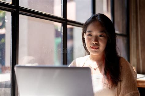 A Focused Asian Woman Is Talking On The Phone With Her Colleague While