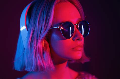 염색 된 머리와 선글라스와 화려한 아가씨는 헤드폰에서 음악을 듣고 네온 빛 배경으로 노래 눈을 감고 춤을 추는 매력적인 힙스터 소녀 관능에 대한 스톡 사진 및 기타 이미지